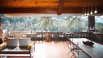 Um terraço com área de estar ao ar livre, bar e vista panorâmica para uma floresta.