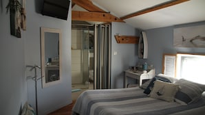 Quarto com cama, escrivaninha, cadeira, espelho e chuveiro.