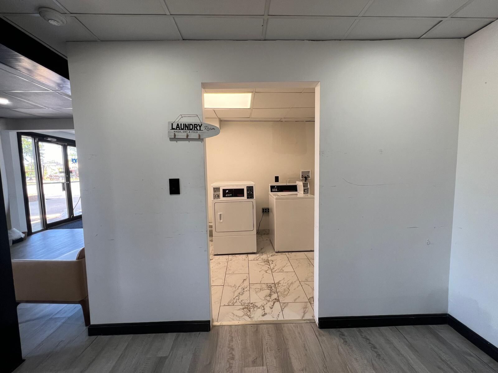 Corredor que leva a uma lavanderia, com placa indicando sua finalidade.