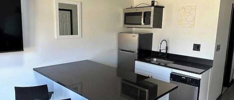 Uma cozinha compacta com uma ilha central, micro-ondas, geladeira e pia.
