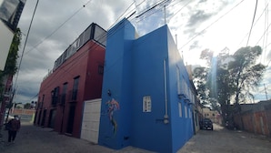 Rua com edifícios, um com porta azul e outro com porta vermelha.