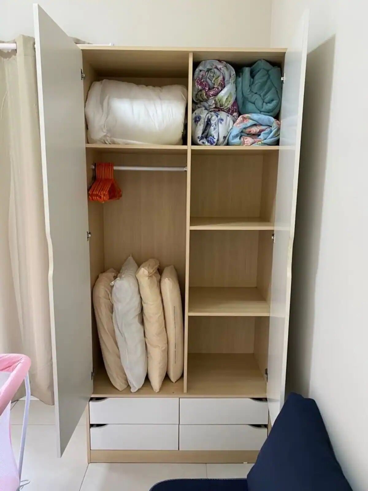 Um guarda-roupa com várias prateleiras e espaço para pendurar, incluindo cobertores e almofadas dobradas.
