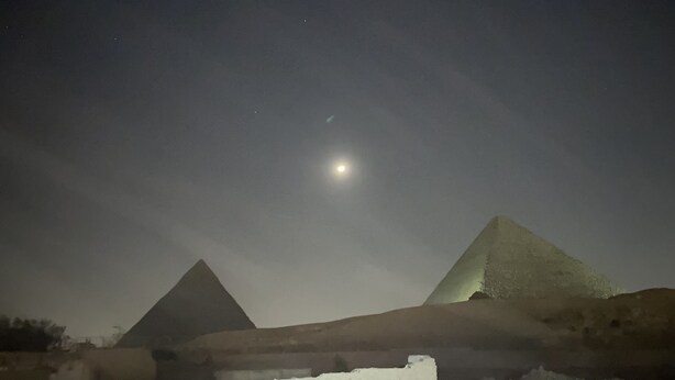 Vista noturna das pirâmides com a lua no céu.