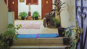 Um hall espaçoso com piso ladrilhado, escada para o andar superior e várias plantas em vasos.