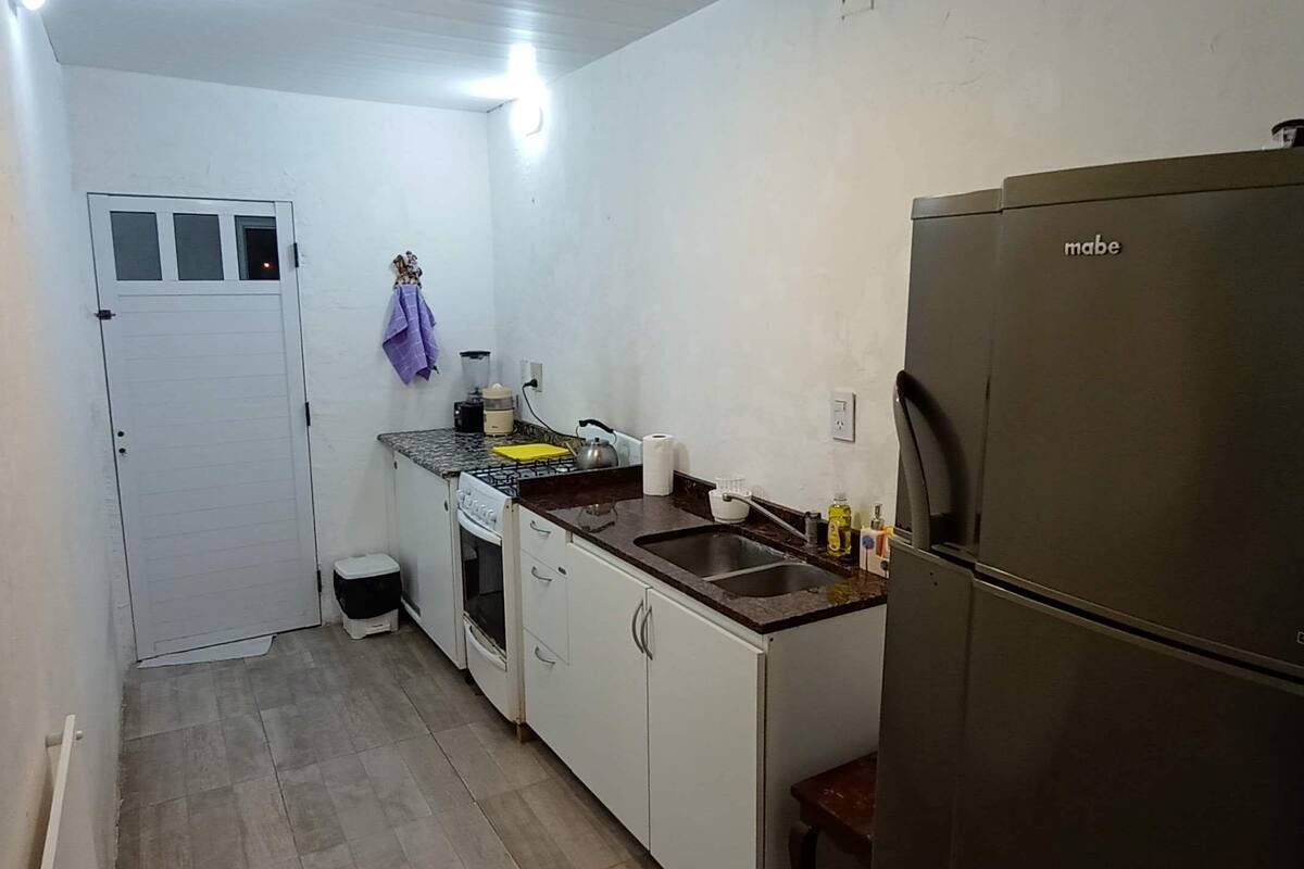 Uma cozinha compacta com geladeira, fogão, pia e um pequeno balcão.