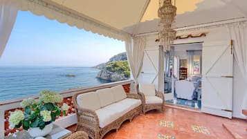 Um terraço com mobiliário de vime, vista para o mar e um candelabro.