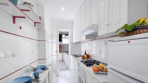 Cozinha moderna com armários brancos, fogão a gás e área de refeições com pratos e talheres azuis.