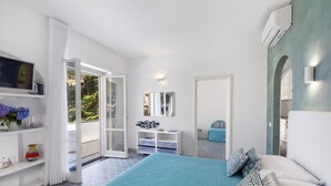 Um quarto com uma cama grande, uma TV em uma estante, uma escrivaninha e um guarda-roupa.