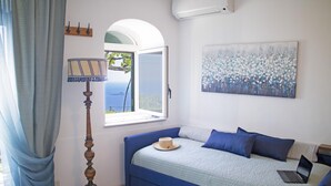Quarto com uma cama, um laptop, uma luminária e um quadro.