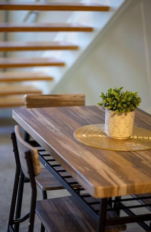 Uma mesa de jantar de madeira com uma planta em vaso e um jogo americano.