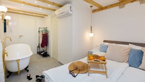 Um quarto moderno com uma cama grande, uma banheira e teto de madeira.