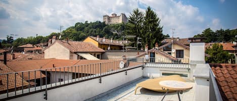 Terraço no telhado com vista para um castelo, rodeado por edifícios residenciais.