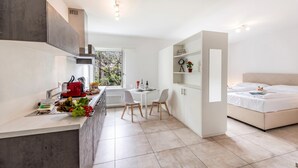Quarto compacto e moderno com cozinha compacta, área de refeições e uma cama.
