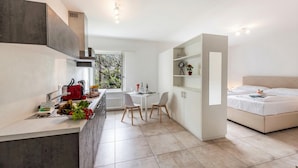 Quarto de hotel compacto com cozinha compacta, área de refeições e uma cama.