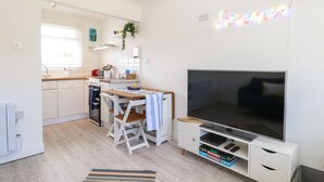 Uma cozinha compacta com área de refeições, TV e um jogo de Scrabble.