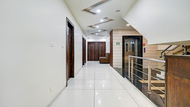 Um corredor moderno com piso ladrilhado, escada com grades de metal e um banco de madeira.