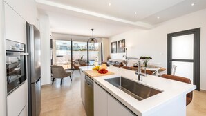 Cozinha moderna com uma ilha grande, eletrodomésticos de aço inoxidável e vista para o terraço externo.