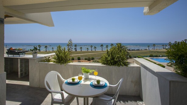 Uma varanda com mesa posta para dois, com vista para a praia e o oceano.