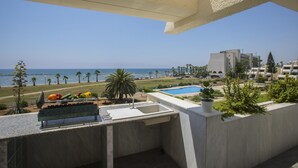 Uma varanda com vista para o mar, uma piscina e um jardim com plantas e vegetais.