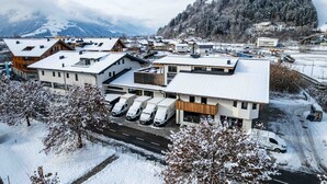 Edifício coberto de neve com várias vagas de estacionamento e vista para uma paisagem montanhosa.