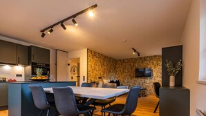 Uma cozinha moderna com área de refeições, piso de madeira e uma TV de tela plana fixada na parede.
