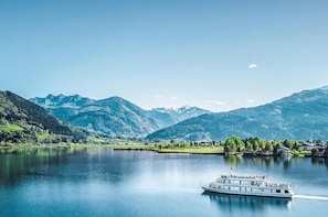Um barco num lago calmo, com montanhas ao fundo.