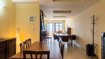 Uma área de refeições com uma mesa e cadeiras de madeira, uma lâmpada e um porta-casacos.