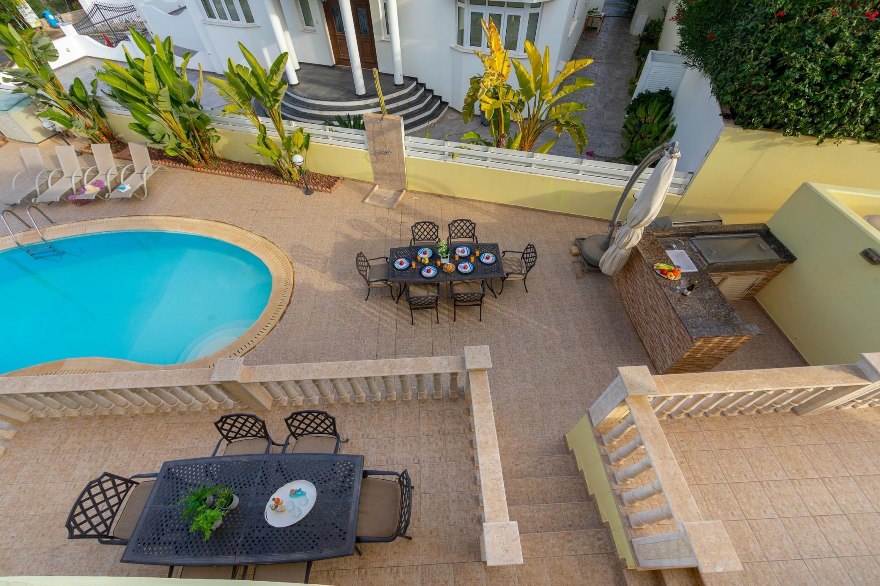 Uma área de piscina no terraço com mesa e cadeiras, uma piscina pequena e vegetação ao redor.