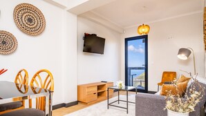 Uma sala de estar moderna com área de jantar, sofá, mesa de centro e TV fixada na parede.