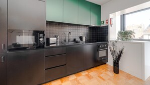 Cozinha moderna com armários escuros, painel de azulejos e janela com vista para prédios.