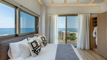 Quarto com uma cama grande, um guarda-roupa e vista para o mar.