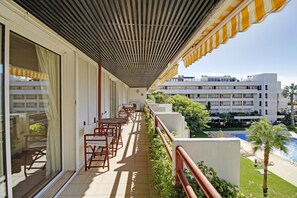 Varanda com móveis de exterior, piscina e vista para um edifício.
