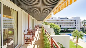 Uma varanda com móveis para área externa, piscina e vista de um edifício alto.