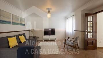 Sala de estar com sofá, televisão e uma cadeira.