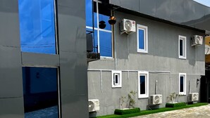 Um edifício moderno com grandes janelas, aparelhos de ar condicionado e um pátio pavimentado.