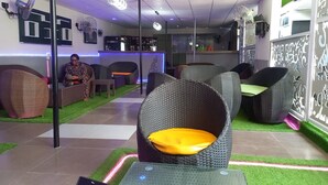 Uma área de estar moderna com cadeiras de vime e um balcão de atendimento.