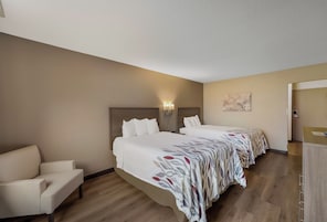 Quarto de hotel com duas camas, um sofá e uma mesa.
