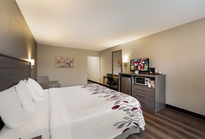Quarto de hotel com cama, escrivaninha, televisão e frigorífico.