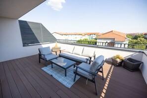 Varanda com mesa e cadeiras, um vaso de planta e vista para prédios.