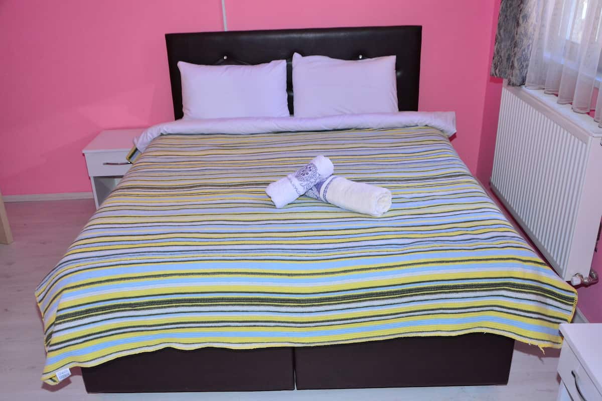 Uma cama com um edredom listrado, duas almofadas e uma toalha enrolada.