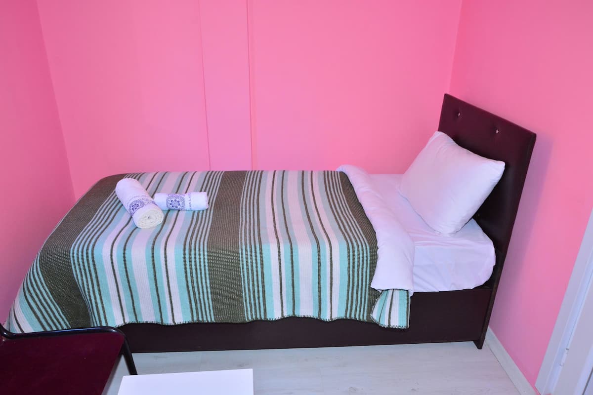 Uma cama de solteiro com um edredom listrado, um travesseiro branco e uma toalha enrolada.
