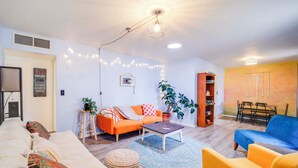 Uma sala de estar com sofá, poltrona, mesa de centro e estante de livros.