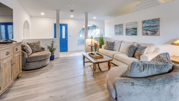 Uma sala de estar espaçosa com piso de madeira, um sofá, uma mesa de centro e um armário.