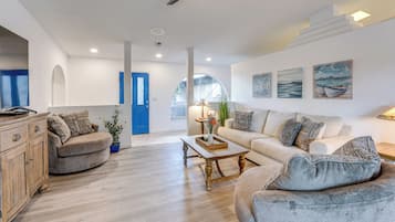 Uma sala de estar espaçosa com piso de madeira, um sofá, uma mesa de centro e um armário.