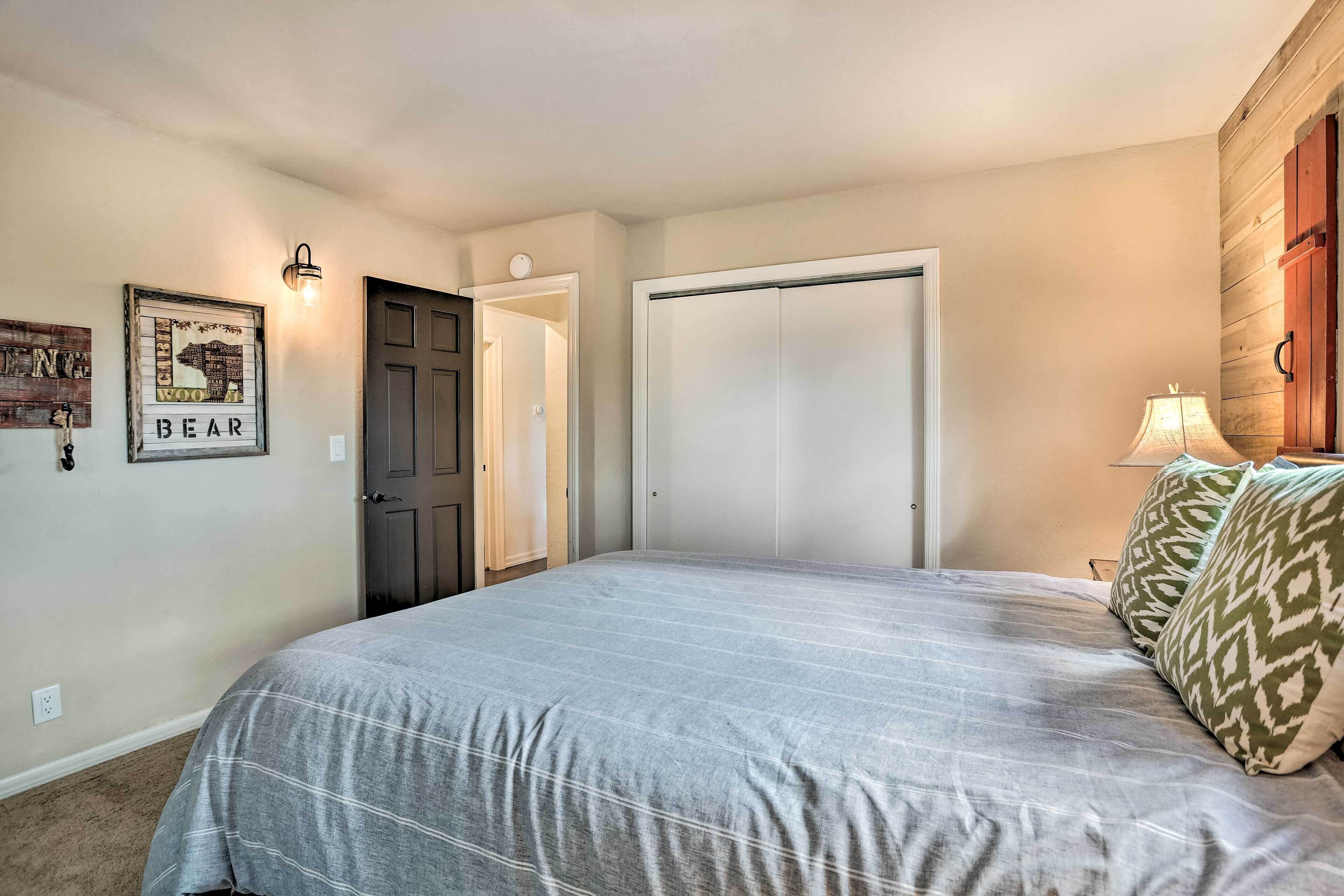 Um quarto com cama, guarda-roupa, porta e luminária fixada na parede.