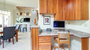 Cozinha moderna com armários de madeira, área de jantar com cadeiras e uma TV.