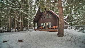 Uma cabana de madeira rodeada por árvores altas em uma paisagem nevada.
