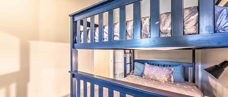 Uma cama beliche com estrutura de madeira e colchão com capa estampada.