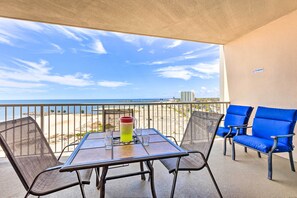 Varanda com mesa, duas cadeiras e vista para a praia e oceano.