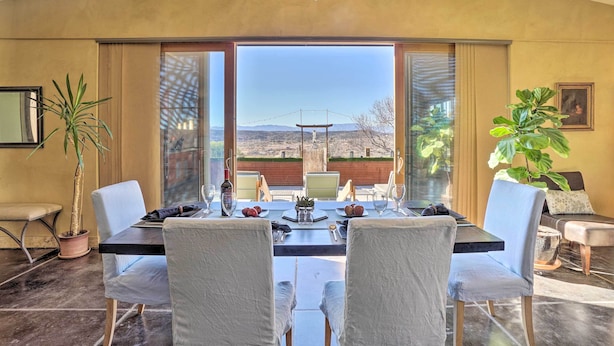 Uma sala de jantar com uma mesa grande, cadeiras e vista para as montanhas.